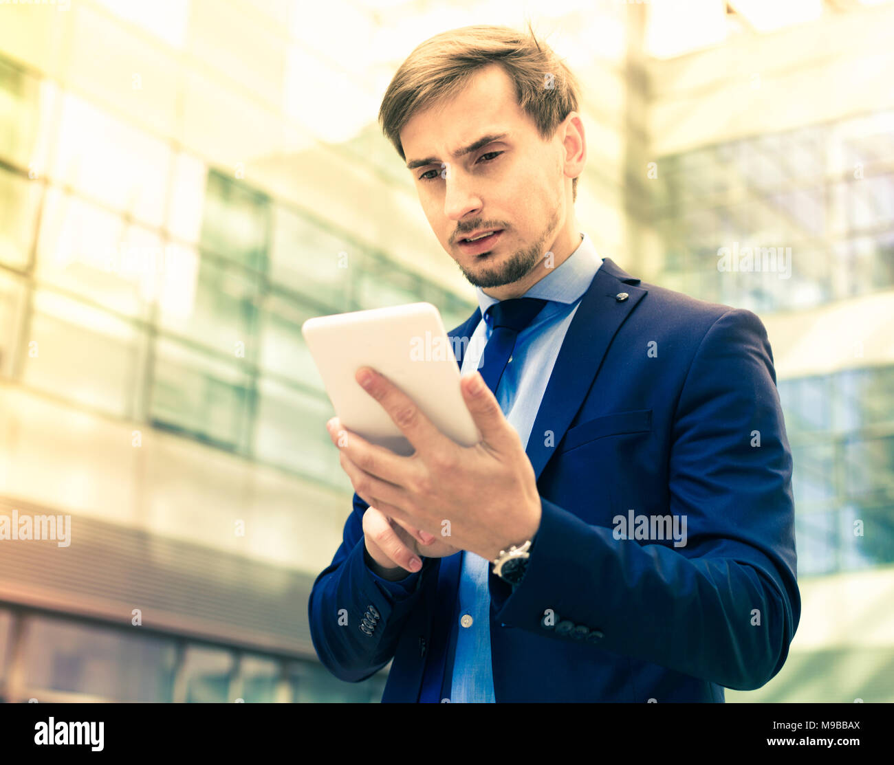 Happy cheerful male testing digital tablet and touchscreen in the big ...
