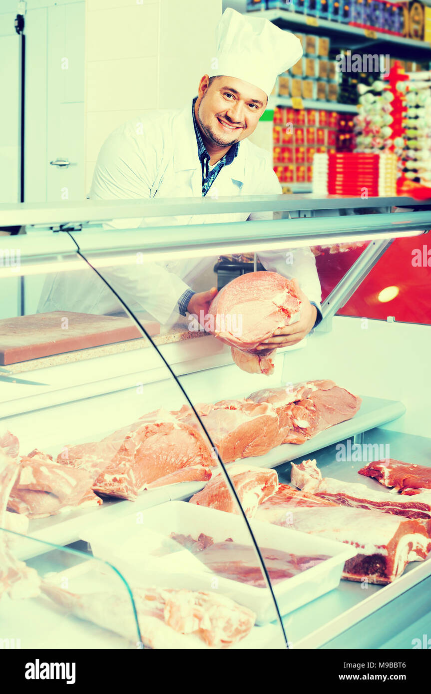 Portrait of positive male butcher in kosher section at supermarket ...