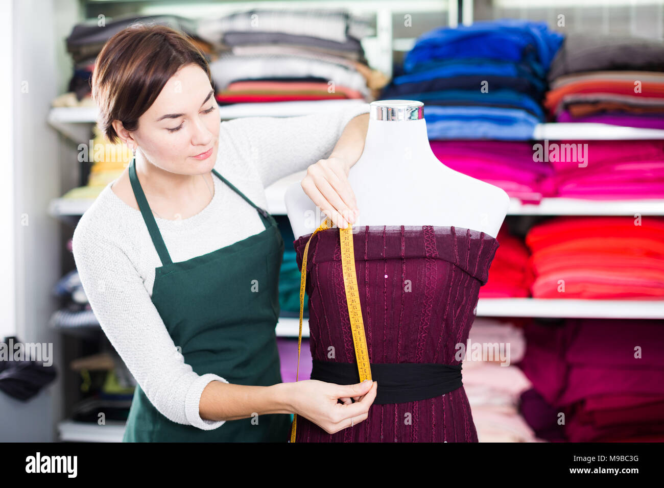 Smiling girl tailor working with mannequin at studio Stock Photo - Alamy