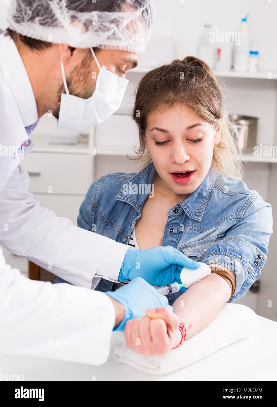 Male doctor using syringe to make injection to young patient in ...