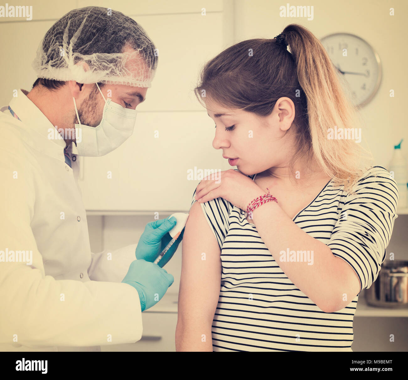 Male doctor using syringe to make injection of vaccine to young patient ...