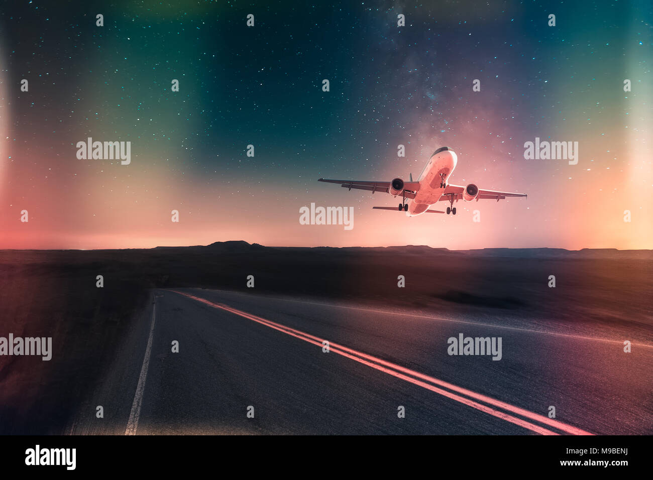 Airplane soaring high in night sky against plain background and road ...
