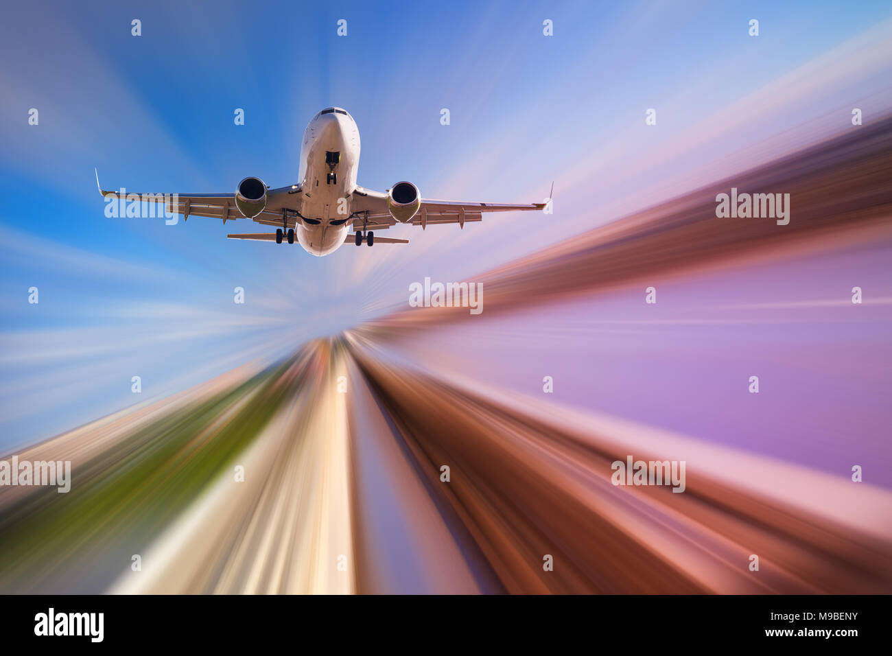 Airplane in motion over roadway on blur blue sky background Stock Photo ...