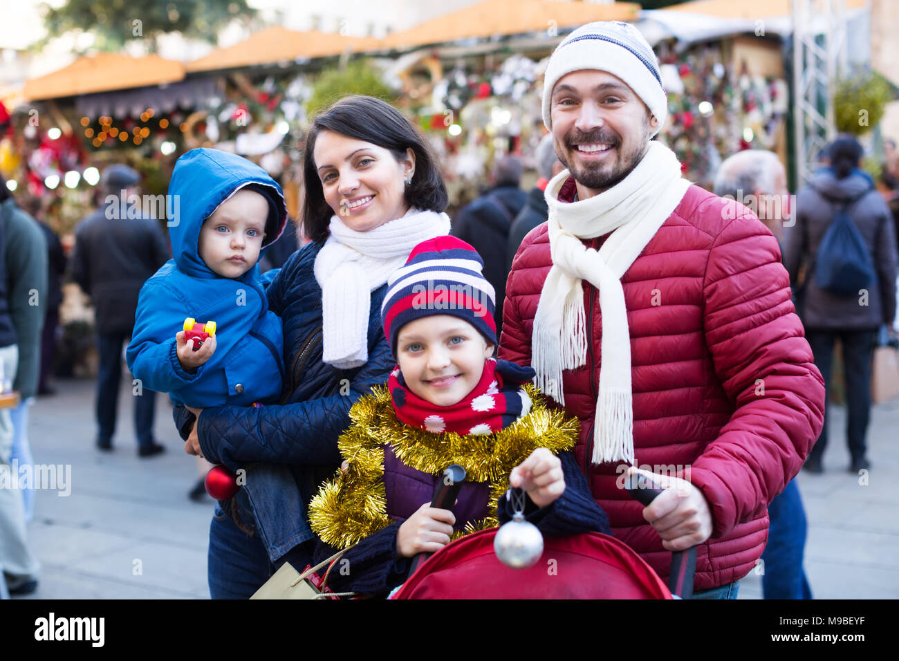 Portrait of smiling family with two children posing outdoors in winter ...