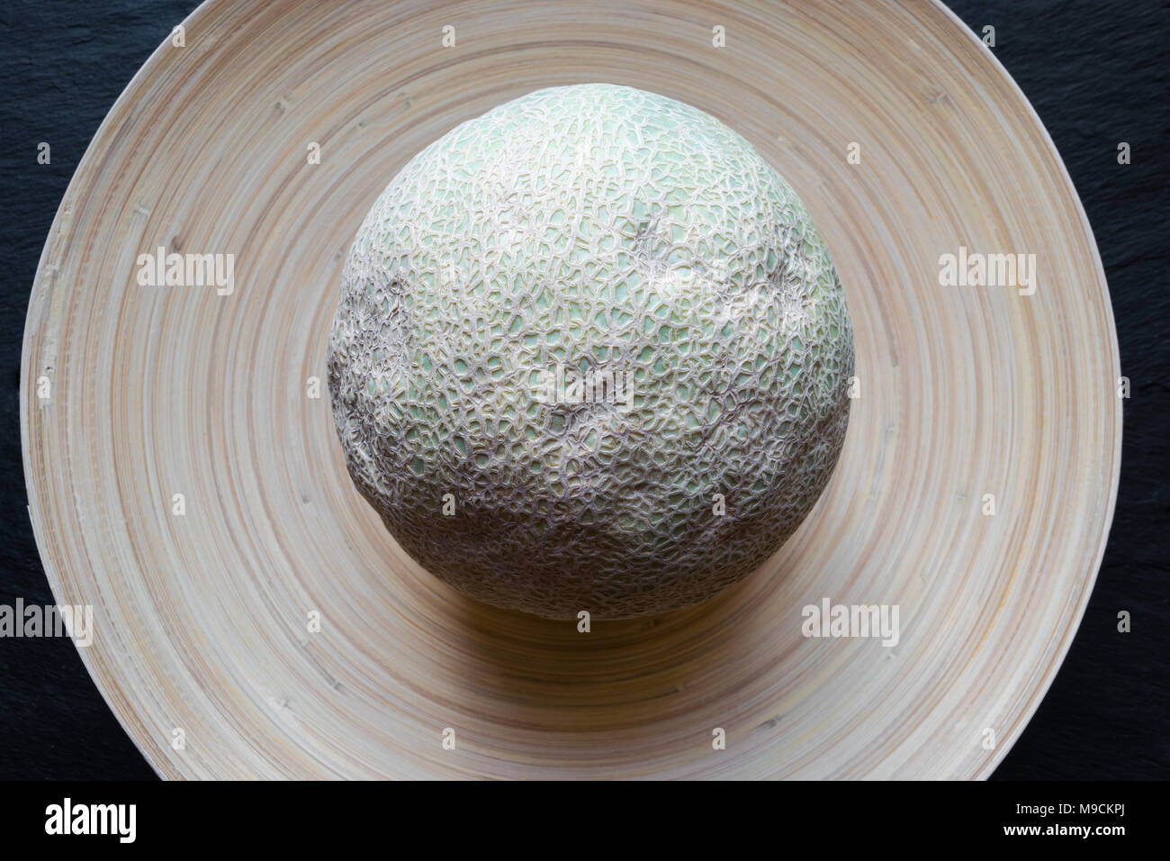 Full head of Hami melon fruit on bamboo plate Stock Photo - Alamy