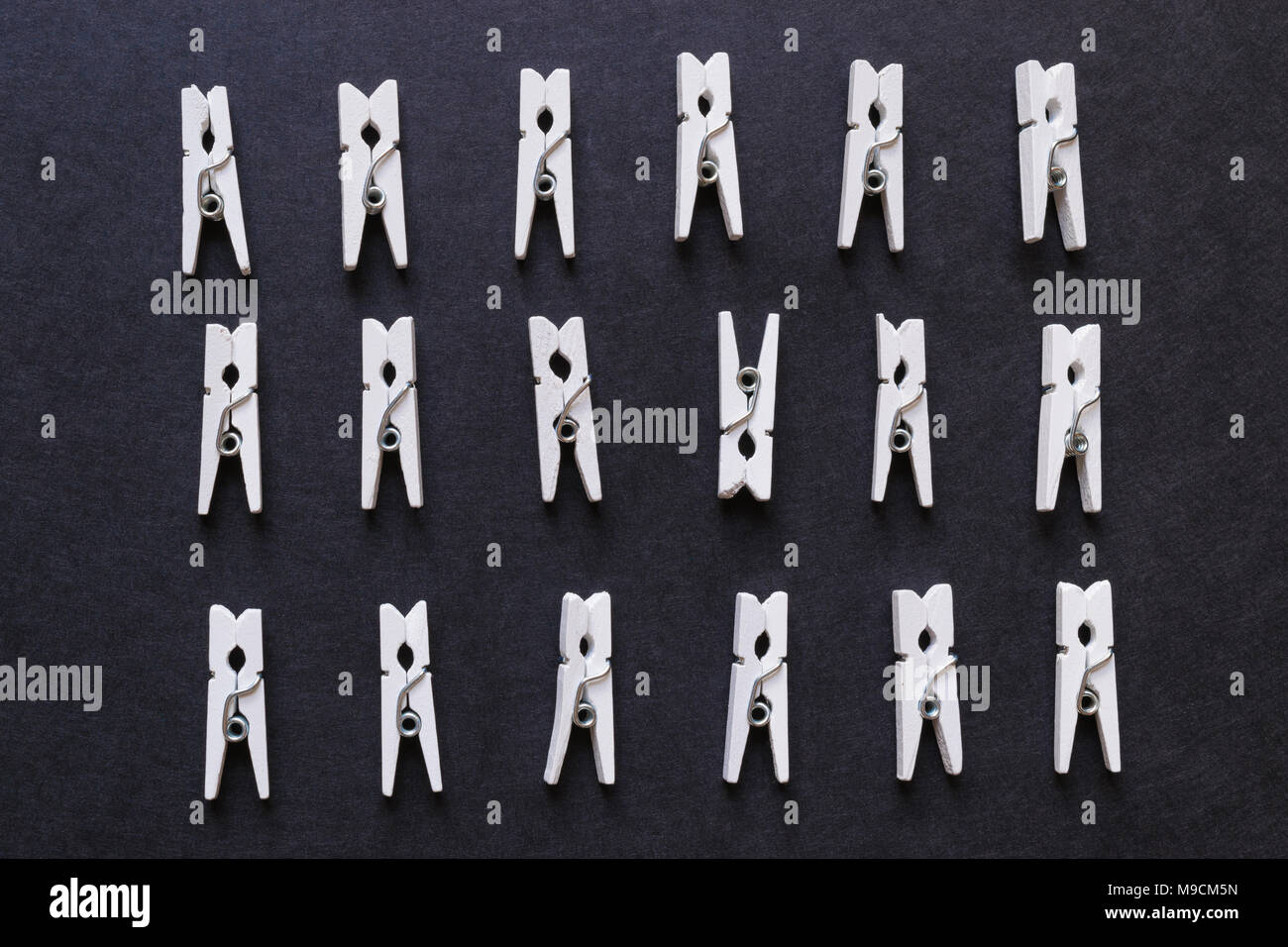 White laundry pins on black surface background. One of the pins ...
