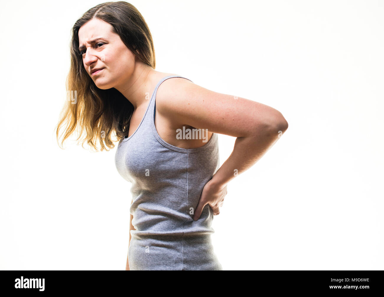 A young Caucasian woman girl wearing a grey vest, suffering from lower ...