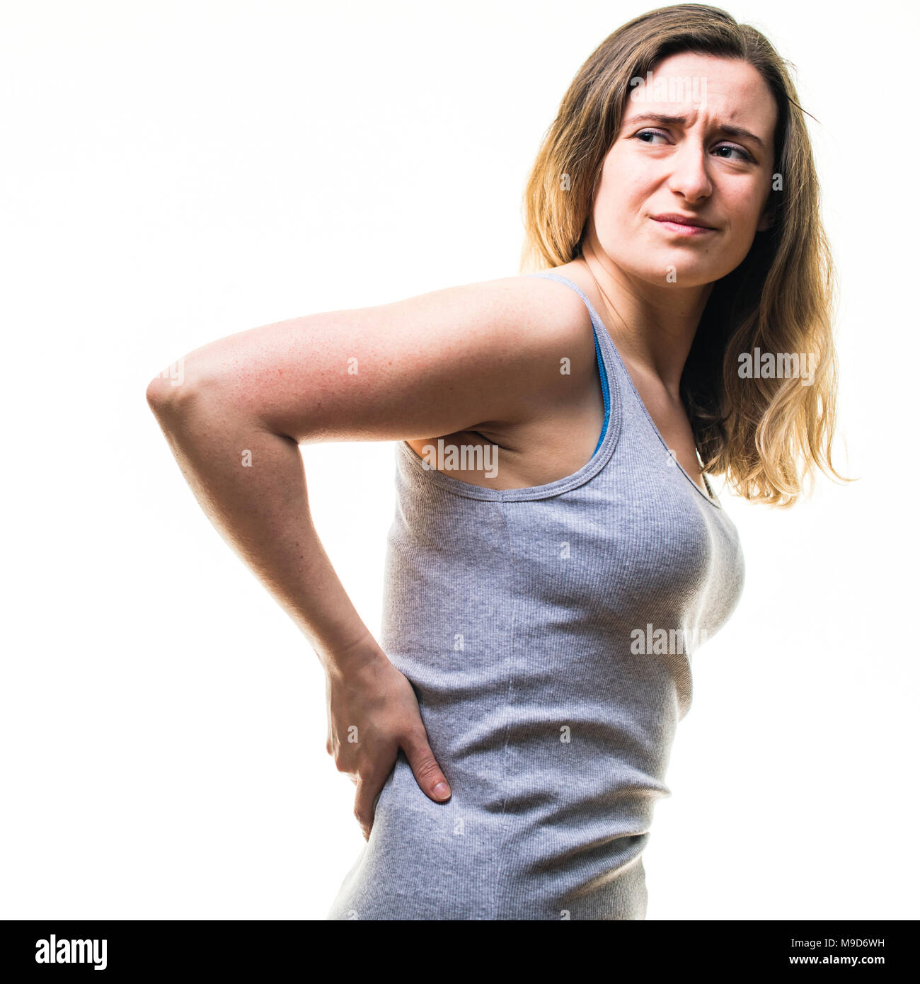 A young Caucasian woman girl wearing a grey vest, suffering from lower ...