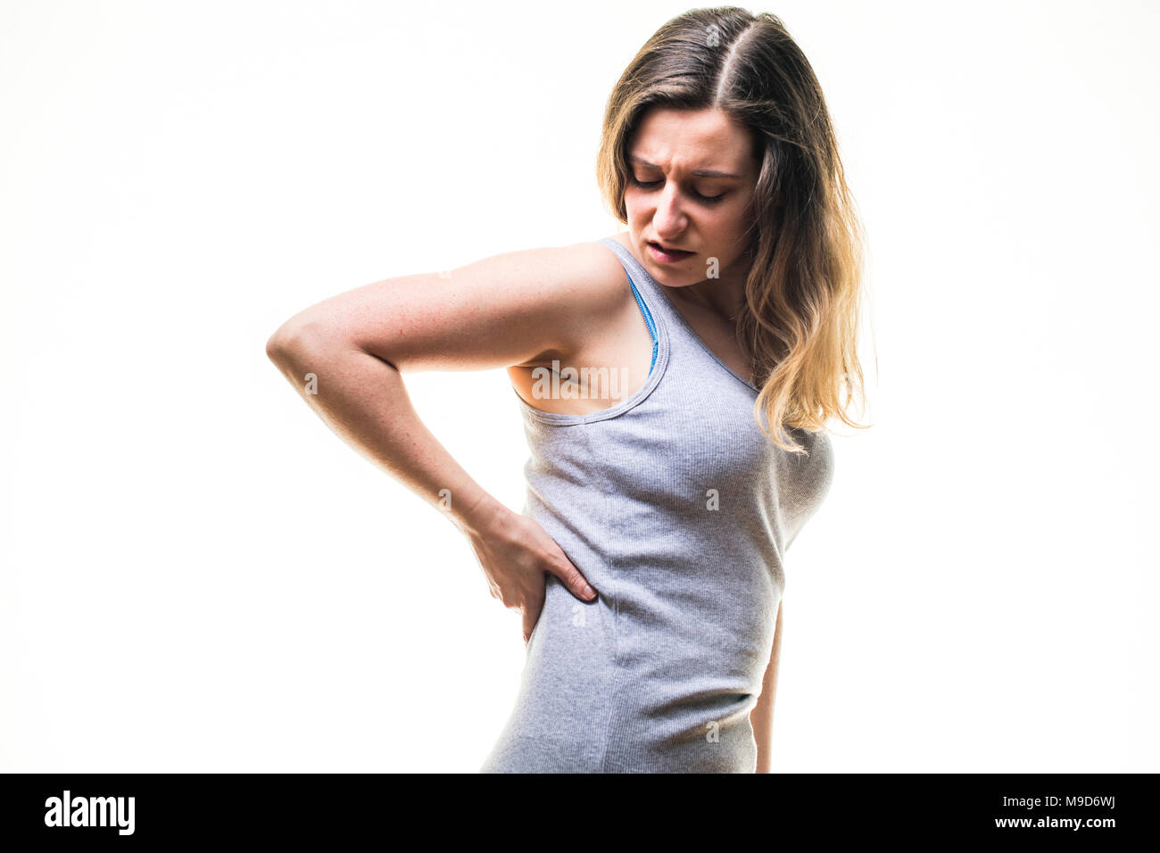 A young Caucasian woman girl wearing a grey vest, suffering from lower ...