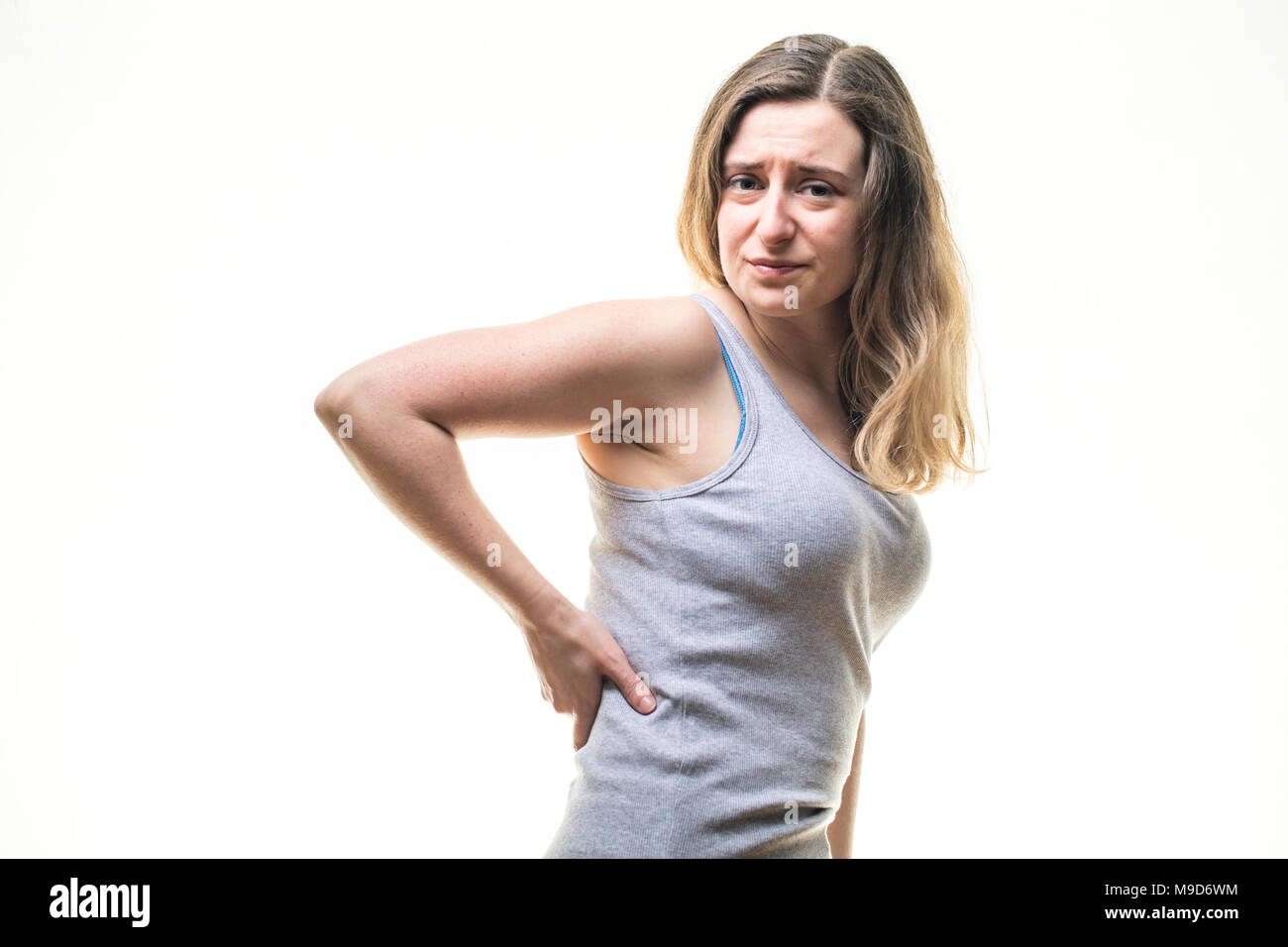 A young Caucasian woman girl wearing a grey vest, suffering from lower ...
