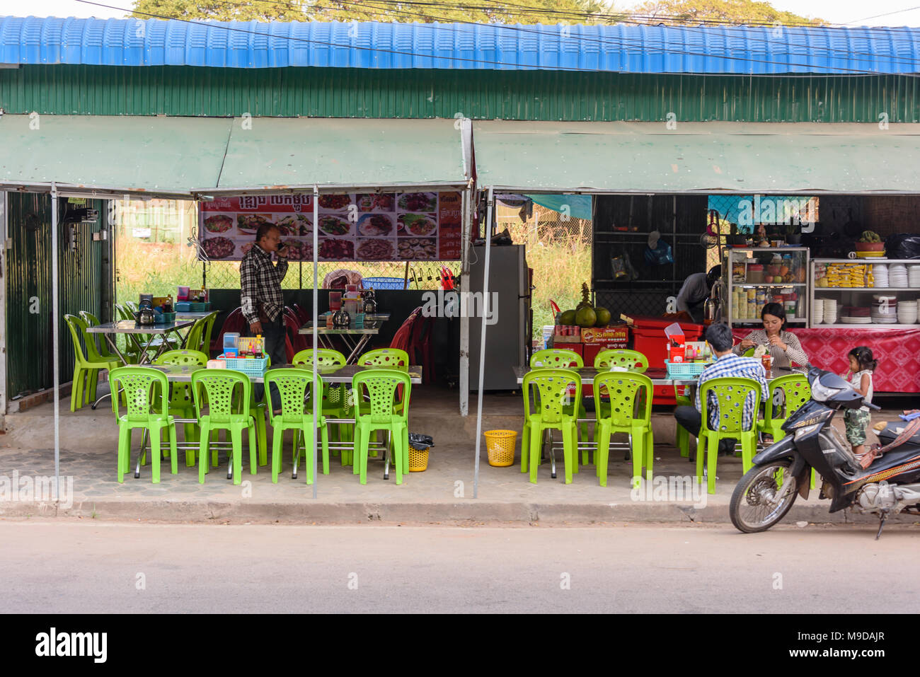 Green plastic chairs at tables outside a street food cafe, Siem Reap ...