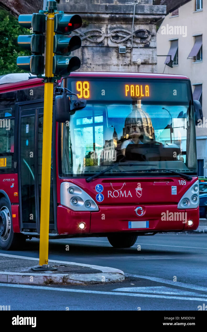Red bus on road with the dome of St Peter's Basilica reflected on the ...