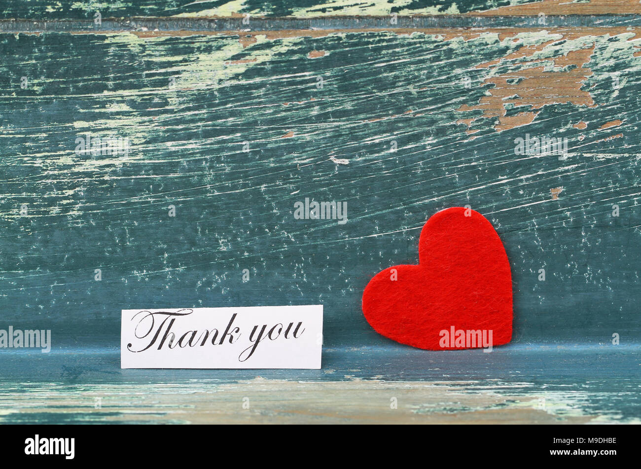 Thank you card with red heart leaning against rustic wooden surface ...