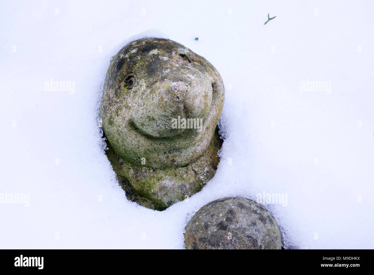 A decorative stone mole garden ornament emerging from the snow Stock ...