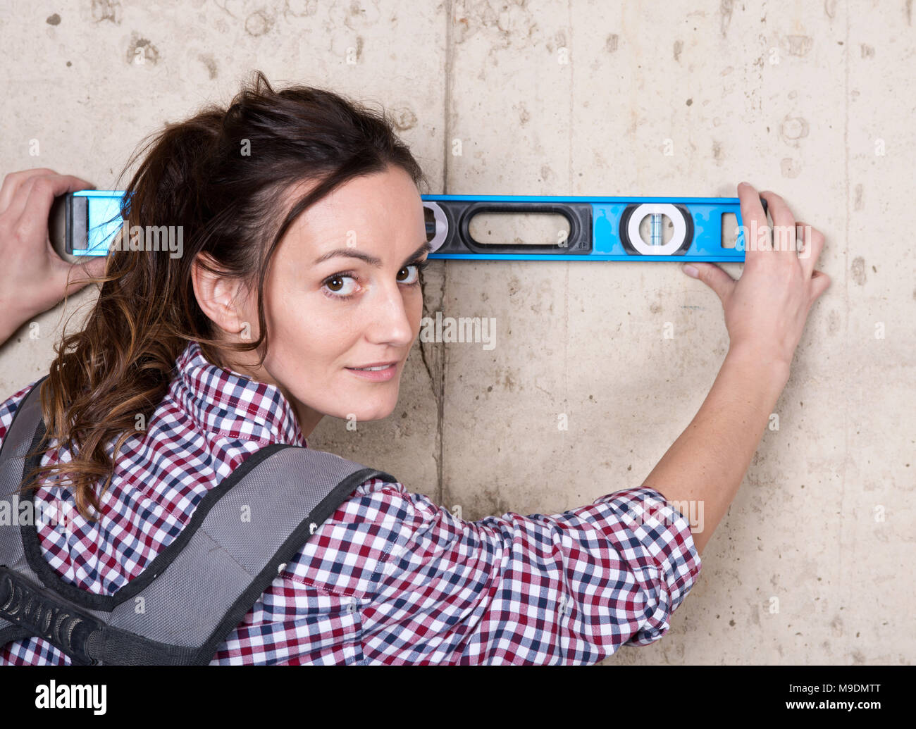 Young woman working with blue builder's standard level in house under ...