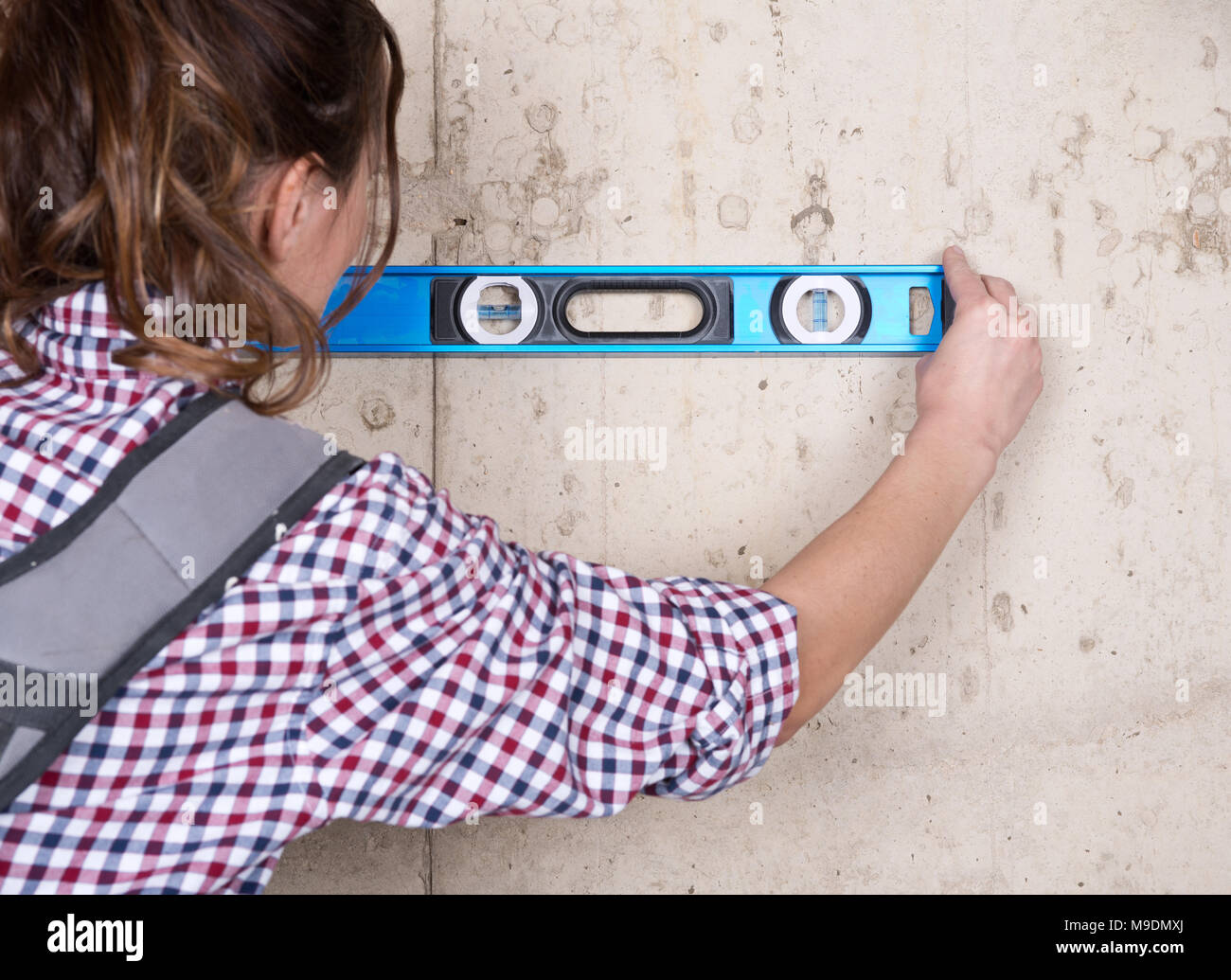 Young woman working with blue builder's standard level in house under ...
