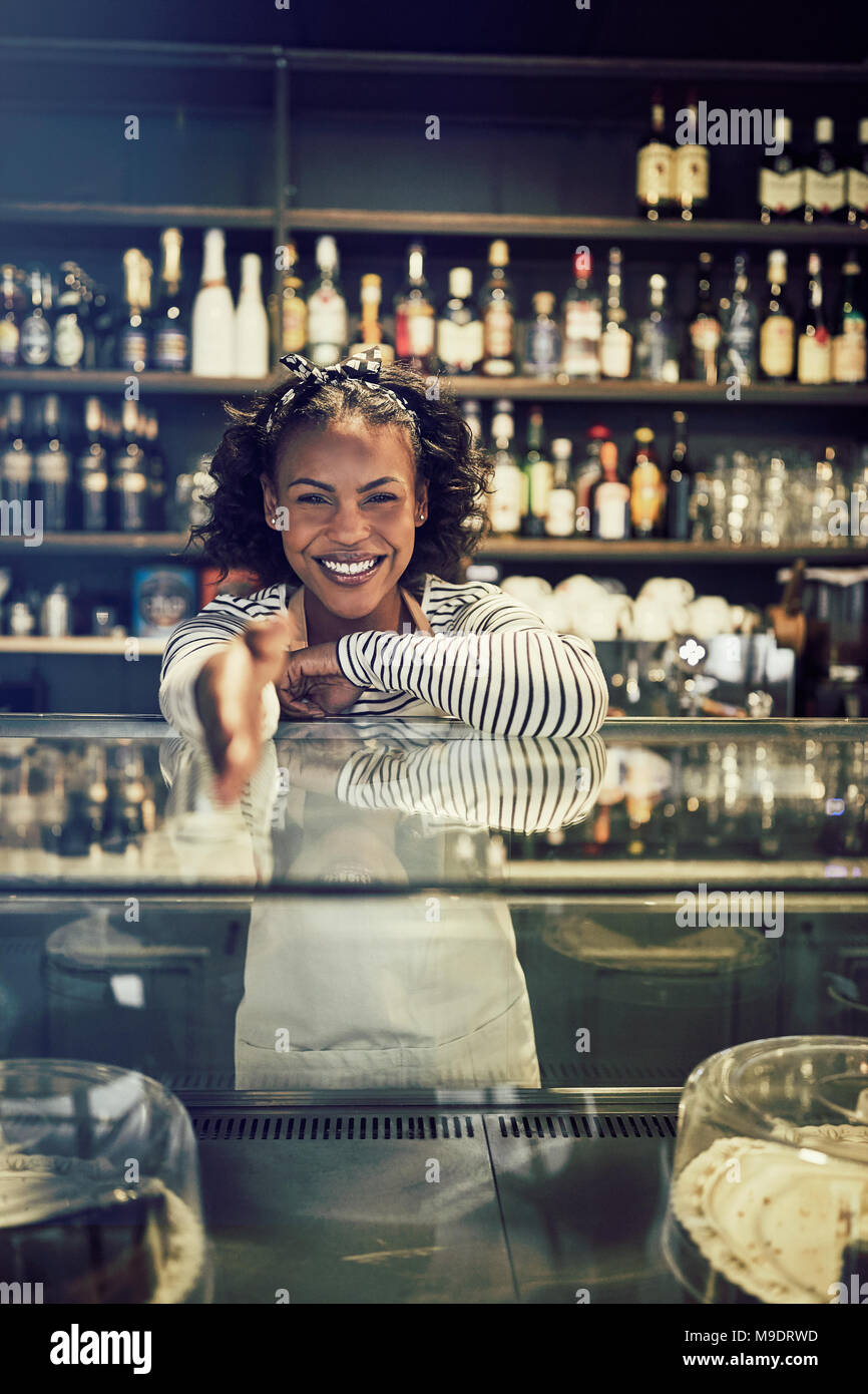 Young African entrepreneur smiling while standing behind the counter of ...