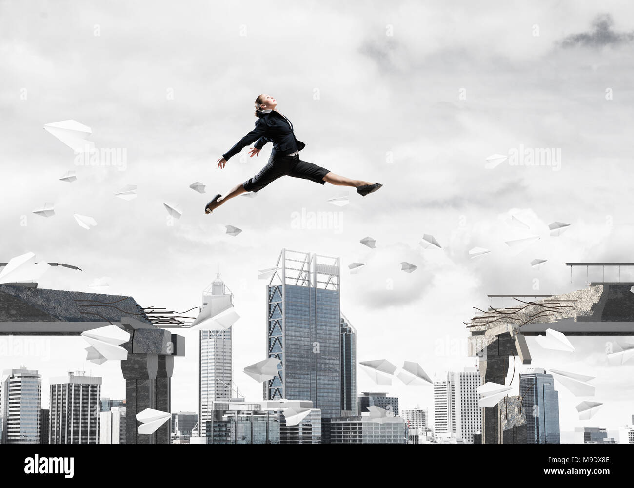 Business woman jumping over gap with flying paper planes in concrete ...