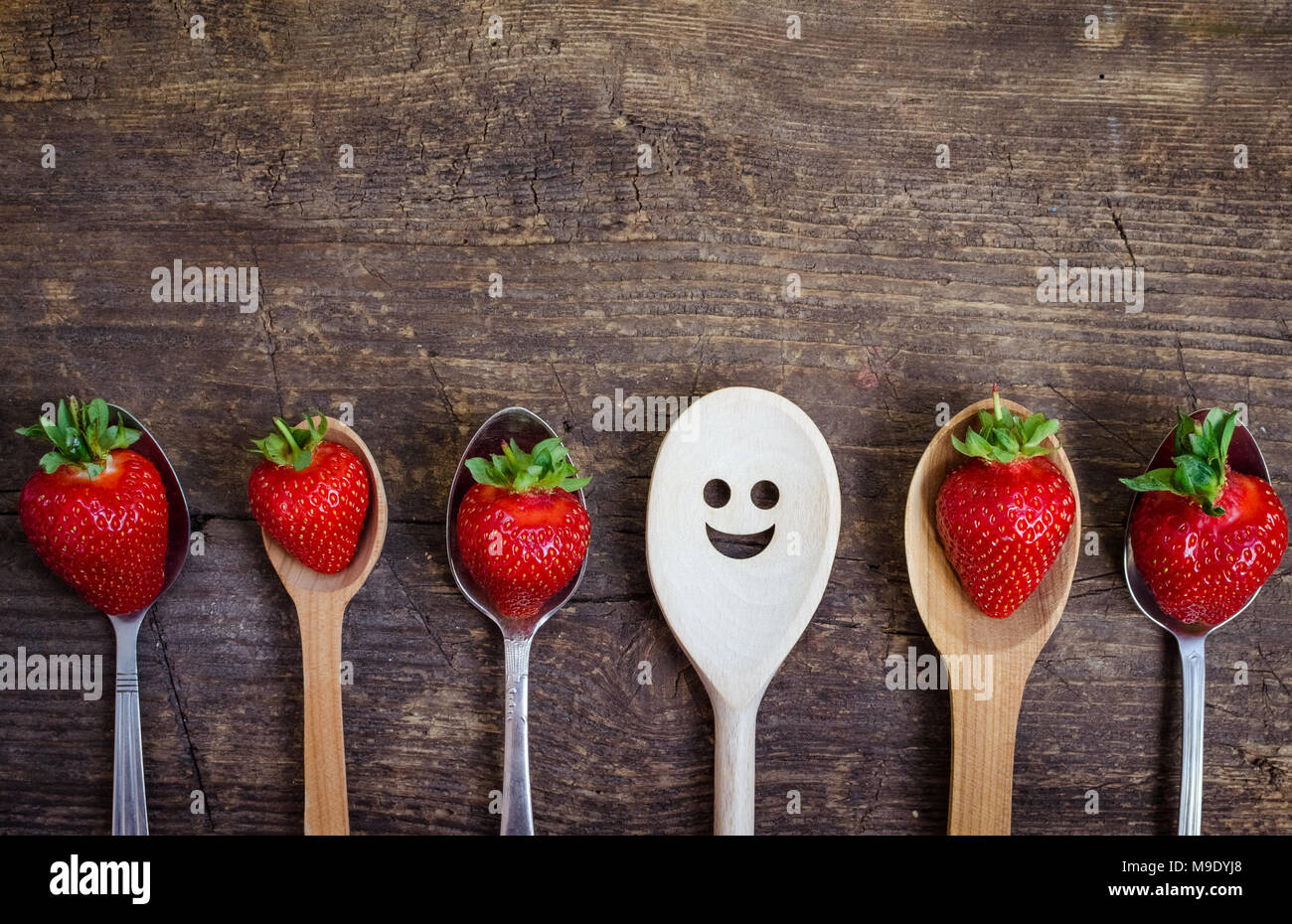 Strawberries on spoons and wooden spoon with smiley face. Stand out of ...