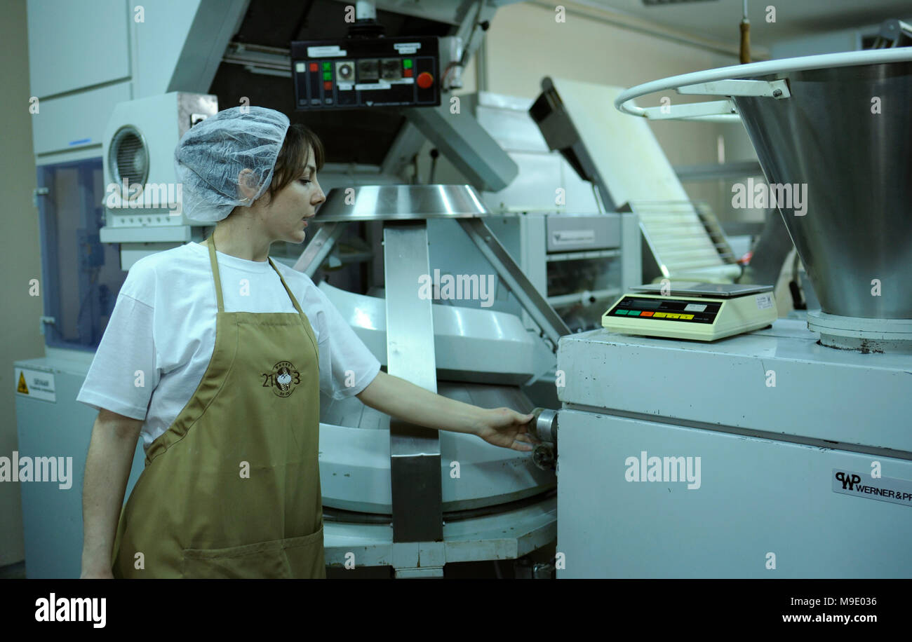 At the Dutch bakery: baker touches a gear-change lever of a bread make ...