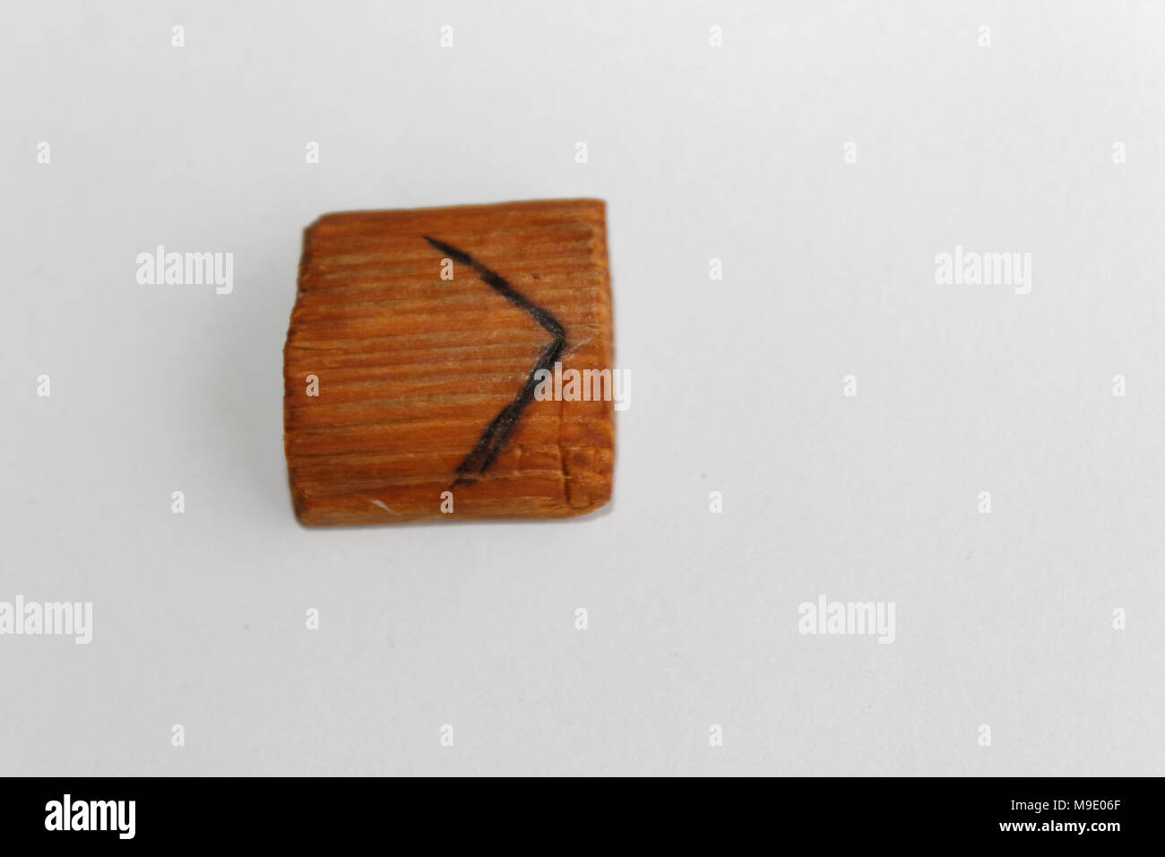 Wooden rune which means ulcer or torch, lie on a table on a white ...