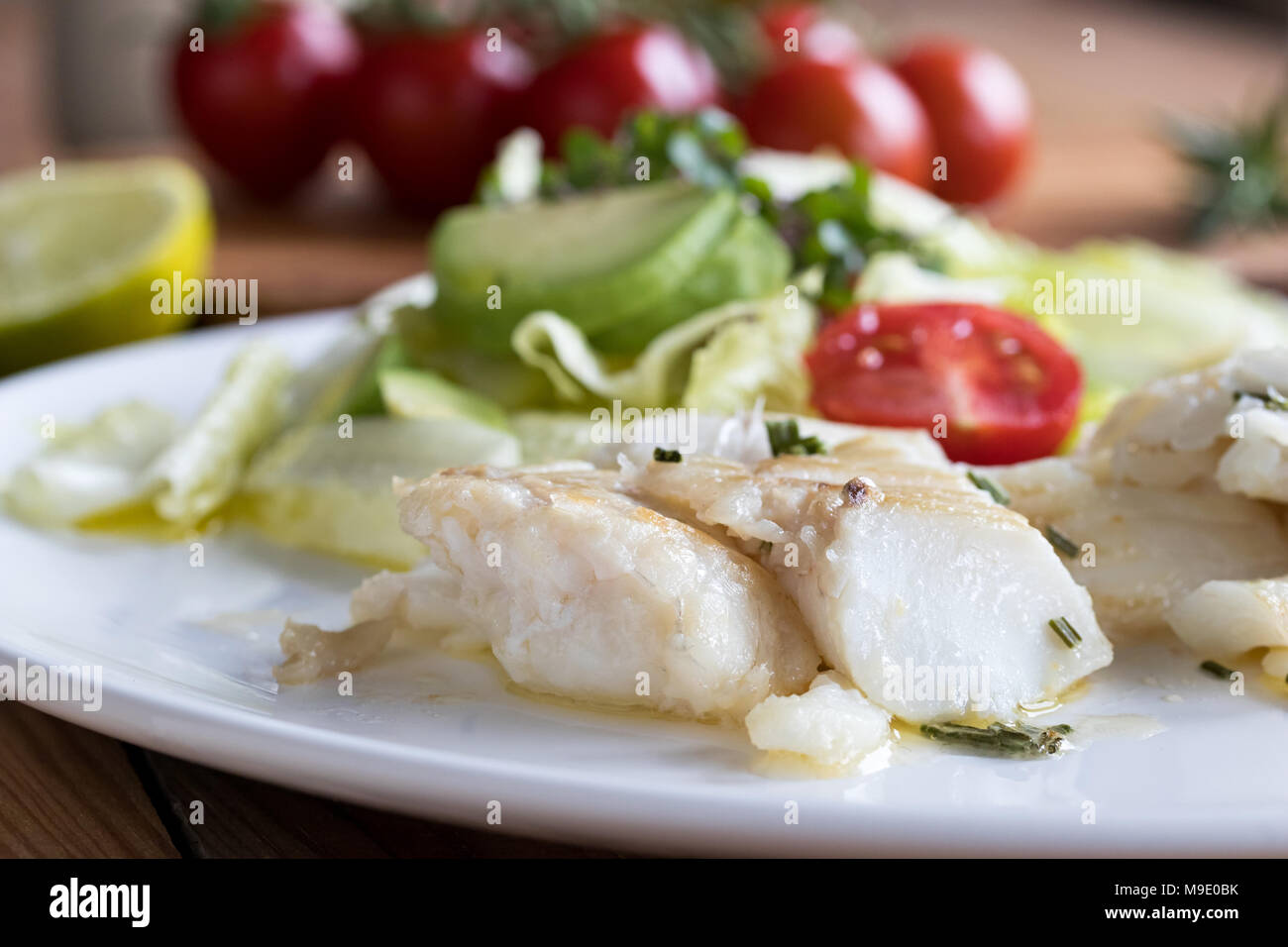 Baked cod fish with vegetable salad in the background Stock Photo - Alamy