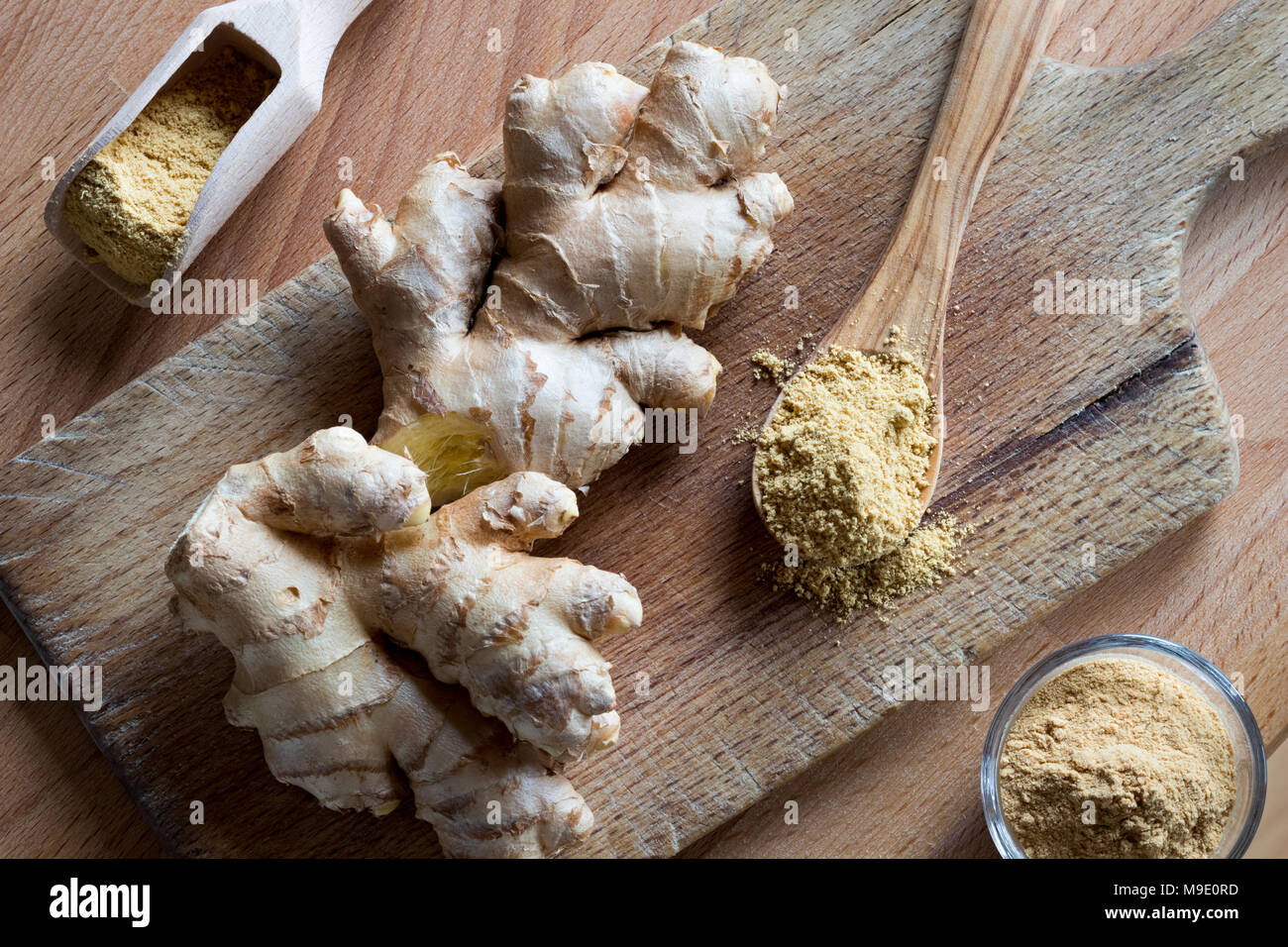 Fresh ginger root and ground ginger on a wooden cutting board, top view ...