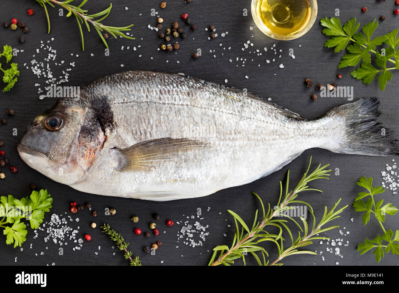 Dorada fish (gilt-head bream) with herbs and spices on a dark ...
