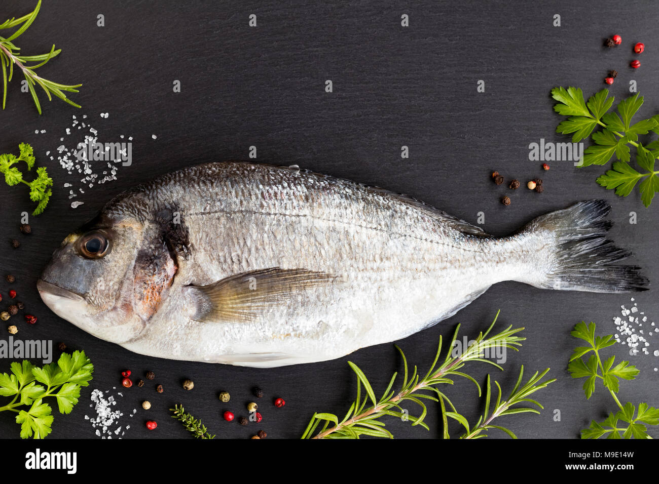 Dorada fish (gilt-head bream) with herbs and spices on a dark ...