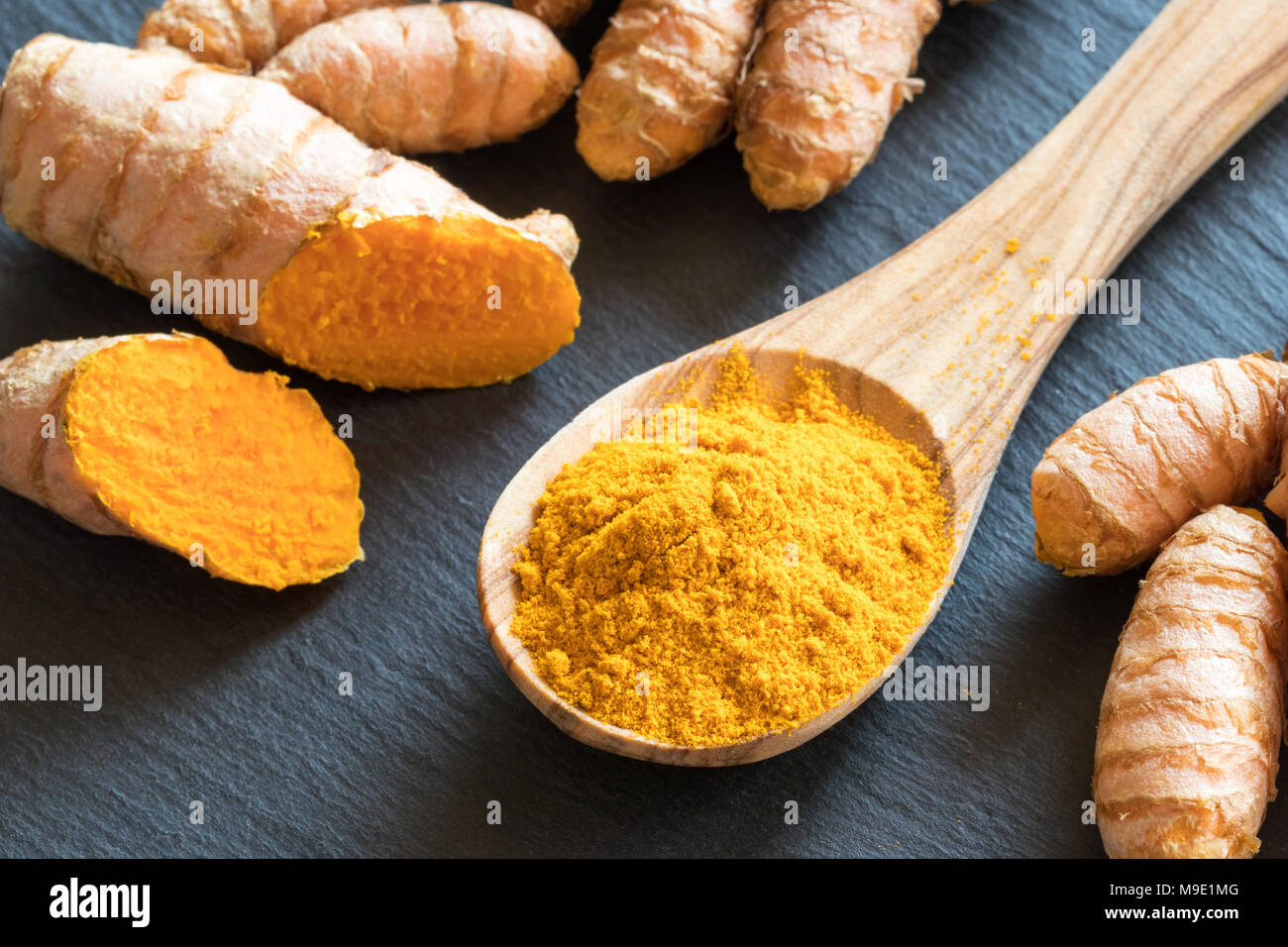 Ground turmeric and fresh turmeric root on a dark background Stock ...