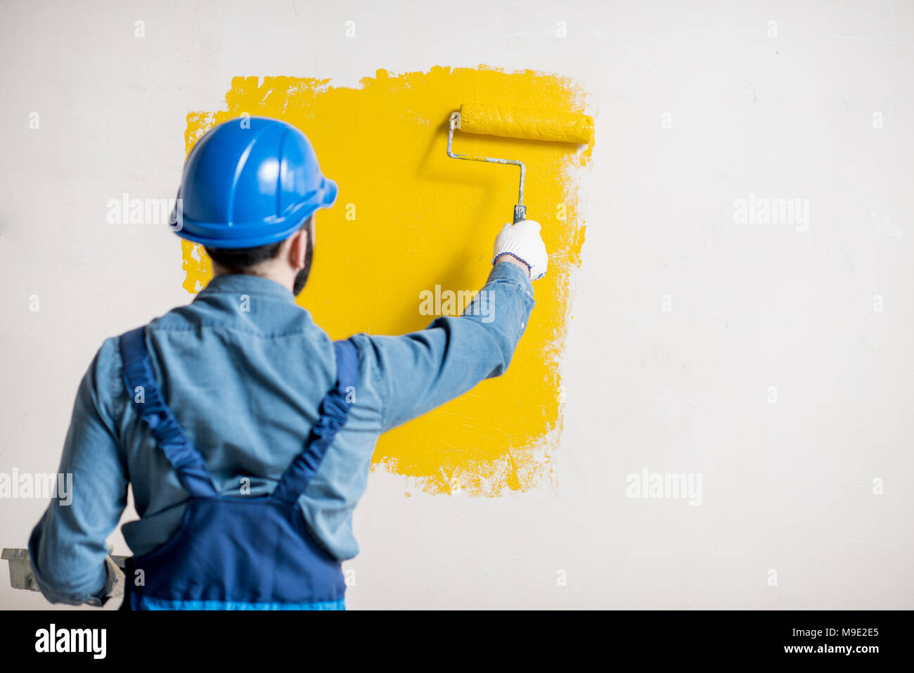 Workamn painting wall indoors Stock Photo - Alamy