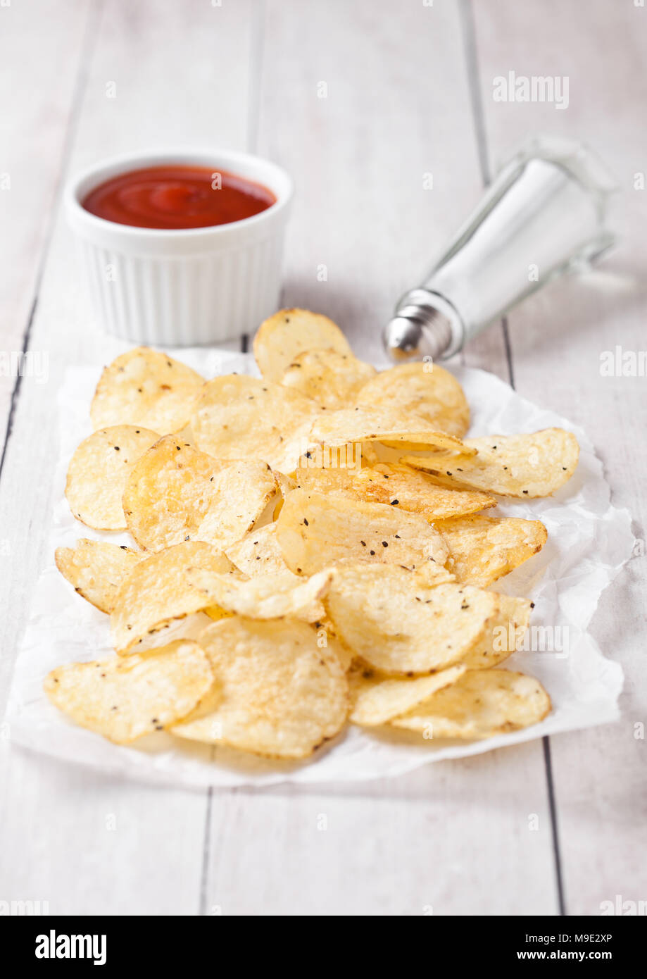 Crispy delicious pepper potato crisps chips snack on white wooden board ...