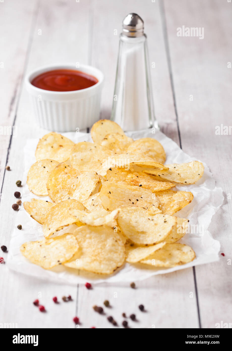 Crispy delicious pepper potato crisps chips snack on white wooden board ...
