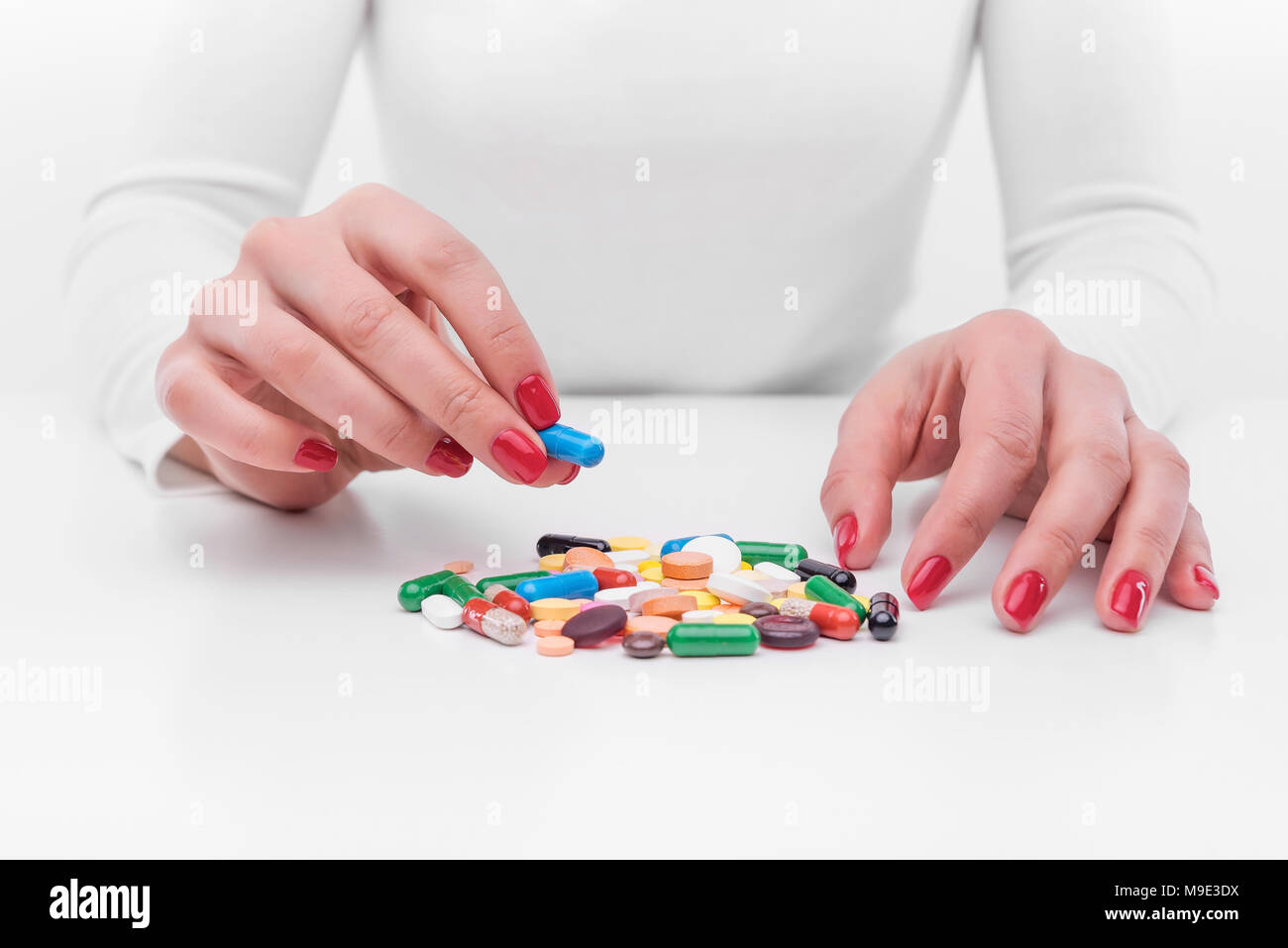 Woman chooses medicine from a handful of different color tablets Stock ...