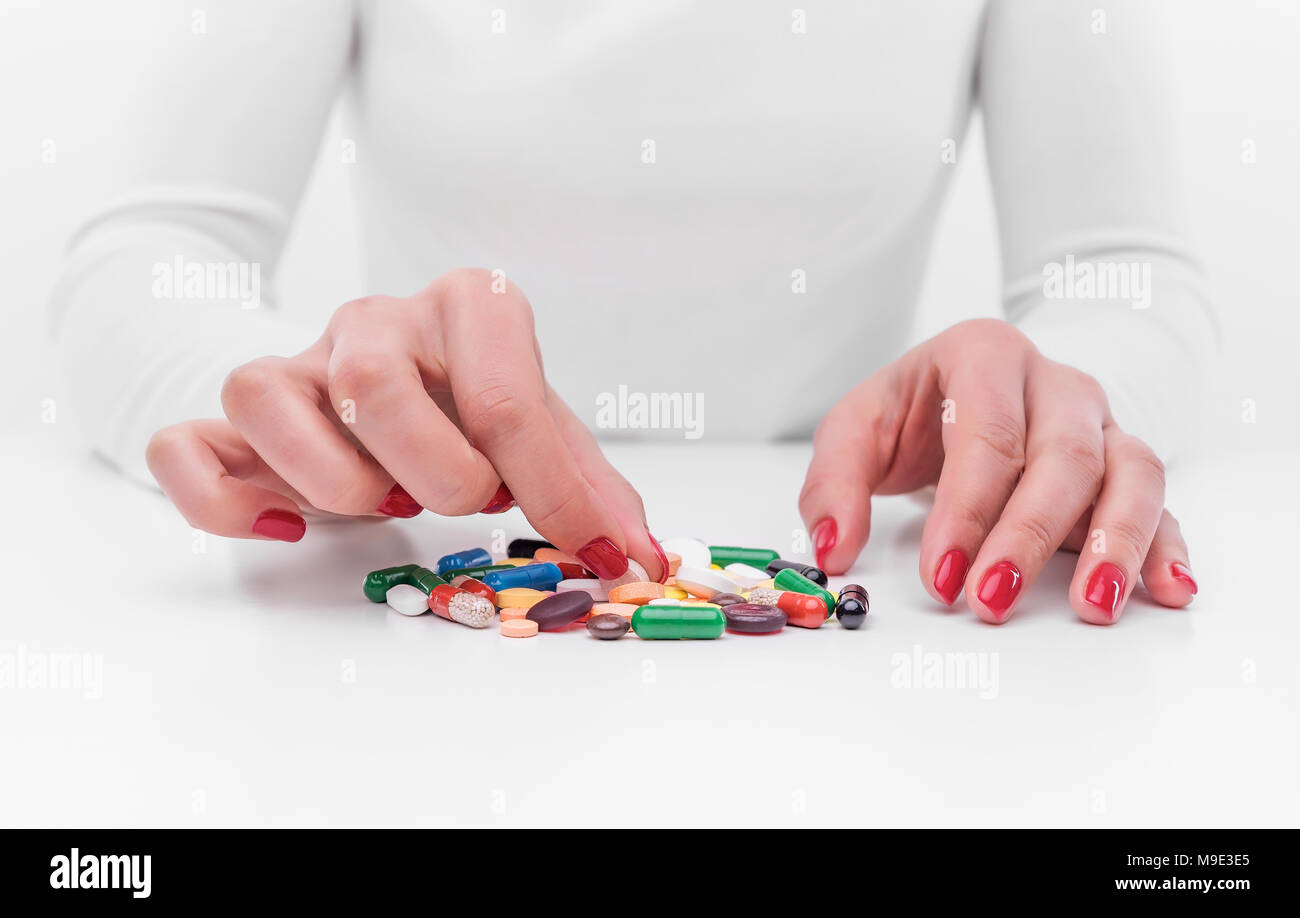 Woman chooses medicine from a handful of different color tablets Stock ...