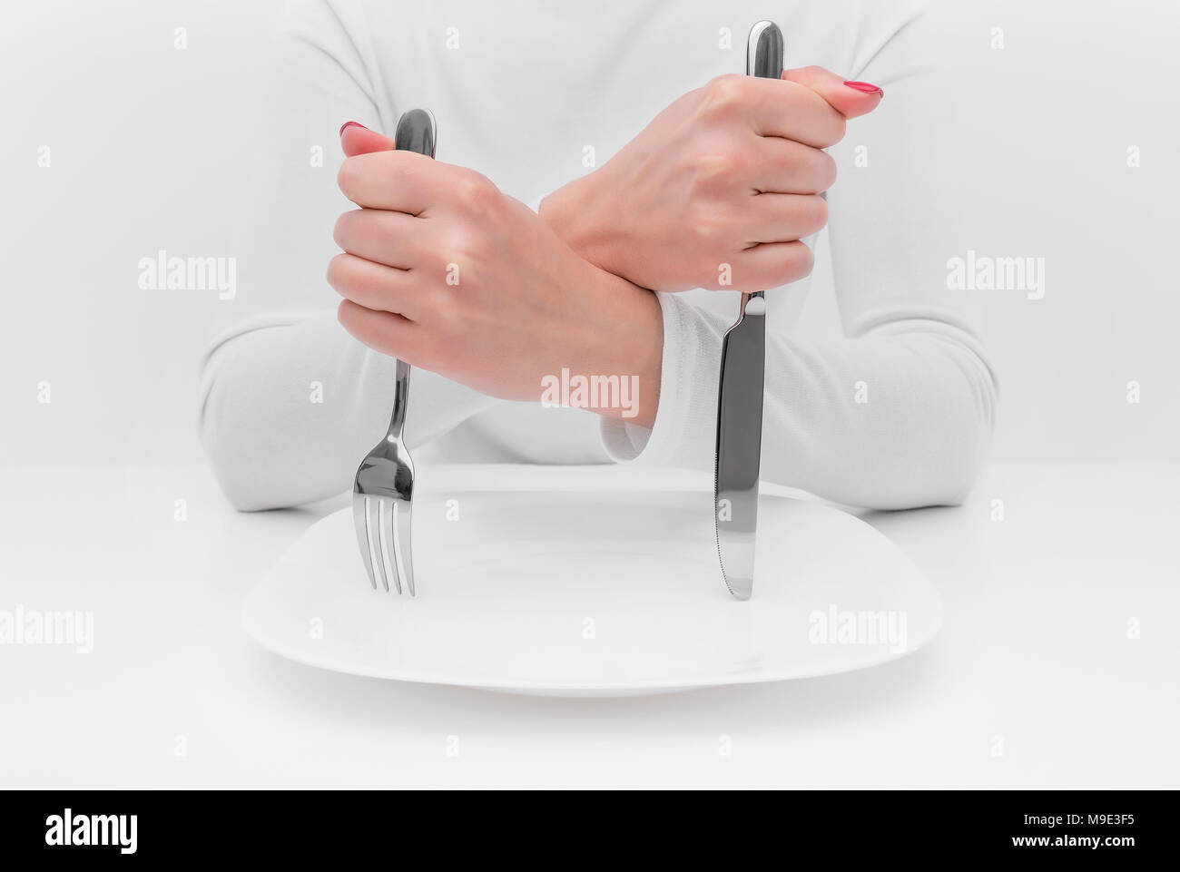 Hands with cutlery over empty plate Stock Photo - Alamy