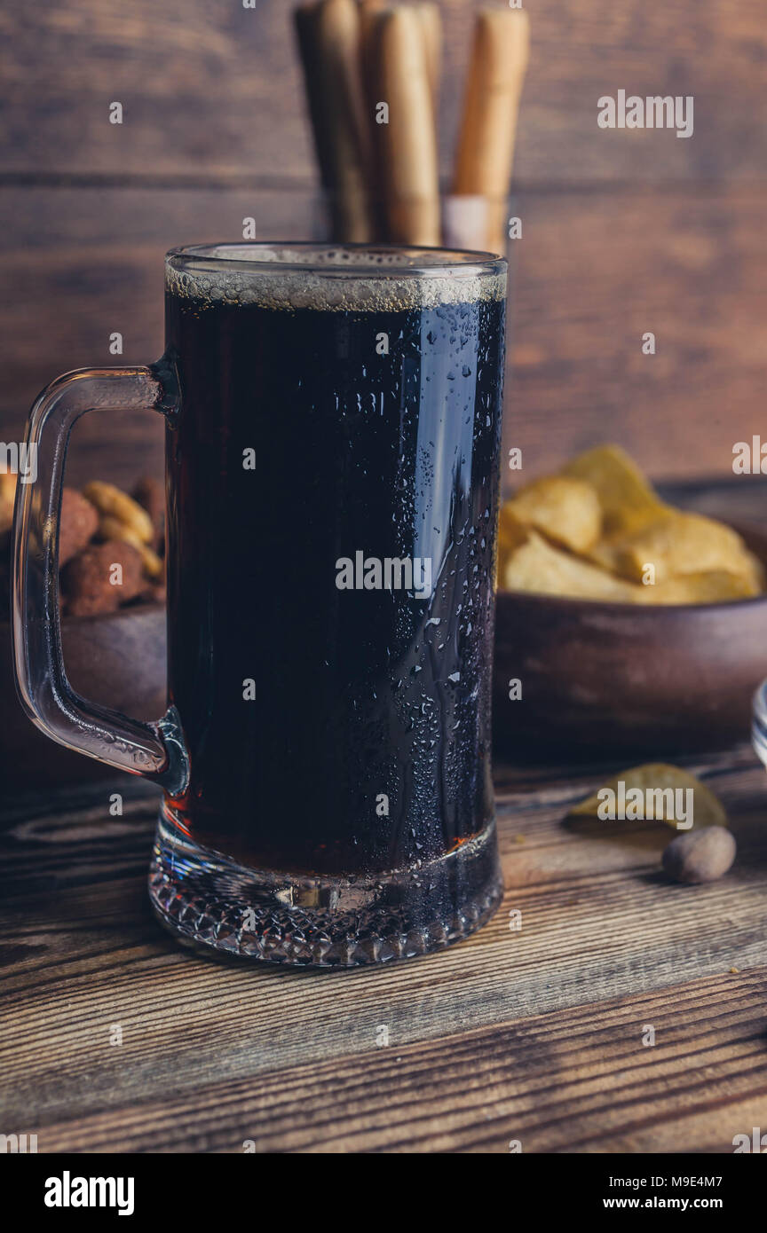 Dark beer in a mug. Snacks for beer on a wooden table. Chips, croutons ...