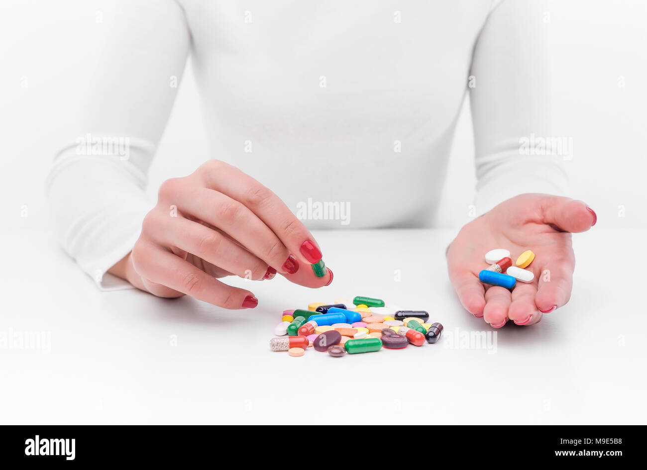 Woman chooses medicine from a handful of different color tablets Stock ...