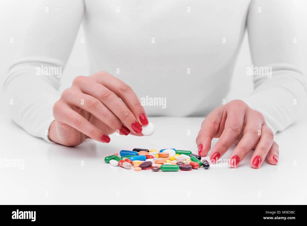 Woman chooses medicine from a handful of different color tablets Stock ...
