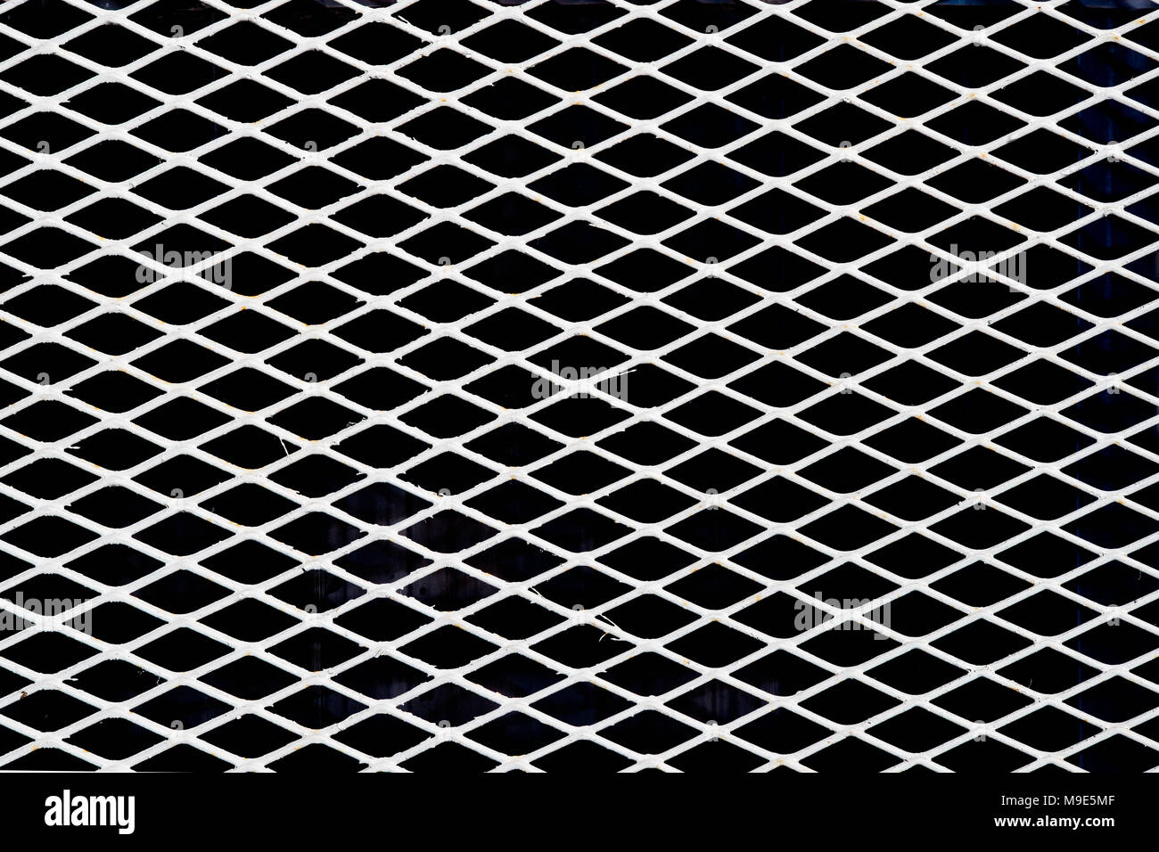 Diagonal white metal wire grid or mesh, black background. Color image ...
