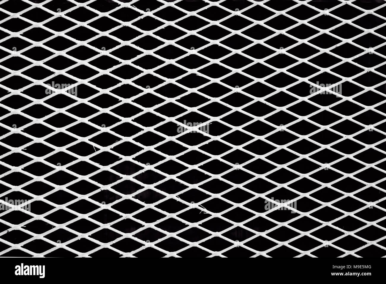 Diagonal white metal wire grid or mesh, black background. Black and ...