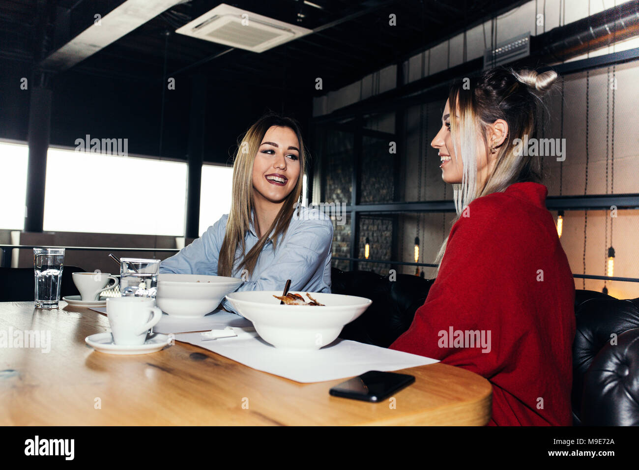 Female friends having lunch together in the modern interior of the ...