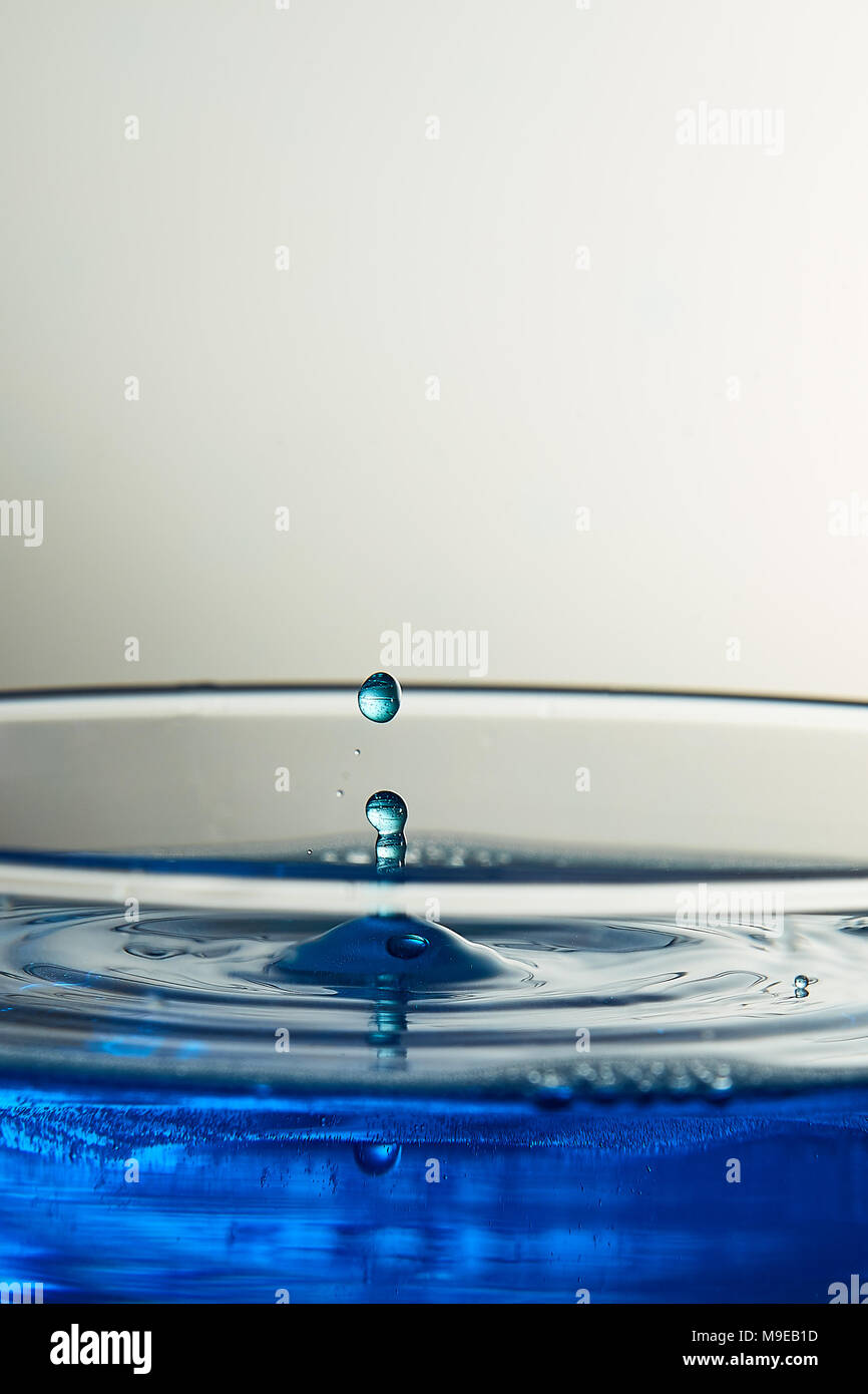 Close up drop in glass with blue champagne or alcohol drink cocktail ...