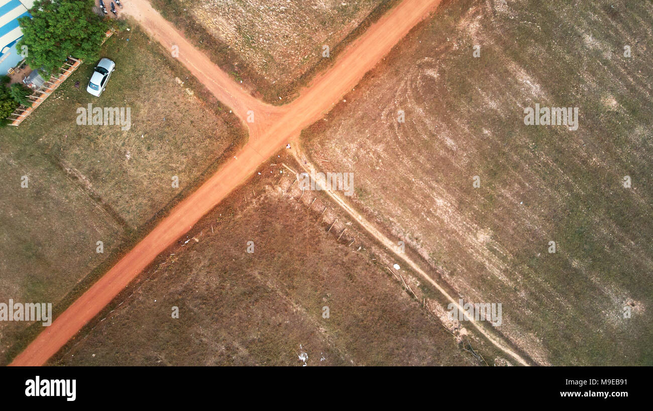 Bird eye eagle view from a drone of a red coloured road crossing rice ...