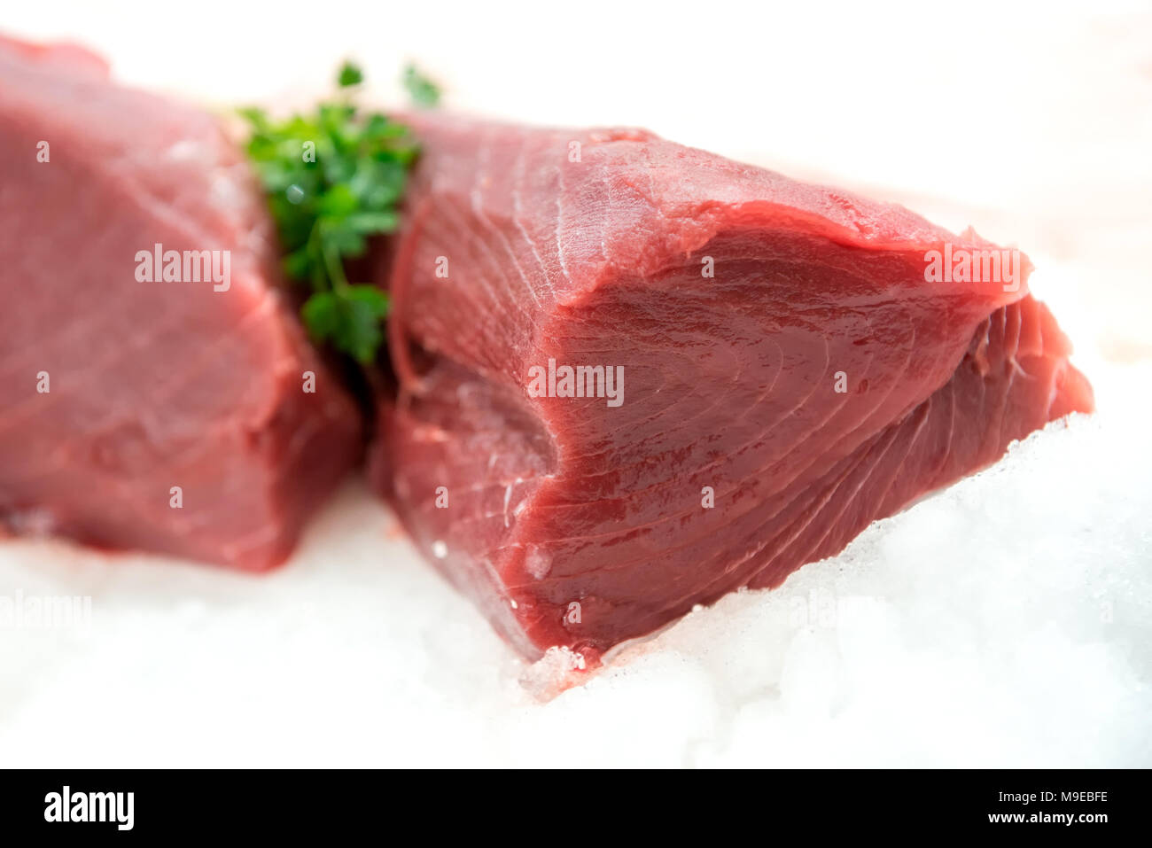 Portion of fresh raw tuna on crushed ice displayed at a fish market or ...