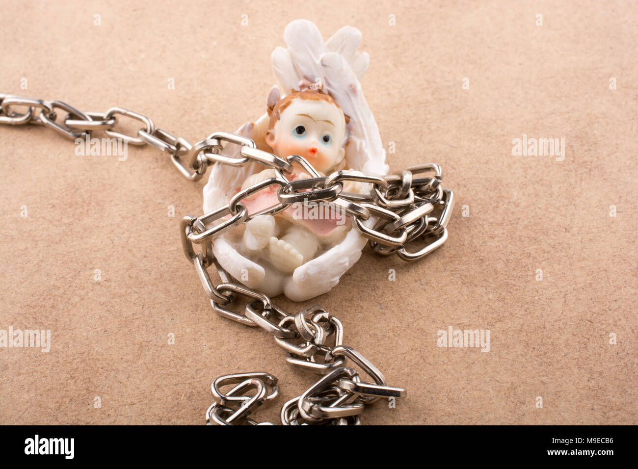 Little baby figure in chains in a cradle on brown background Stock ...