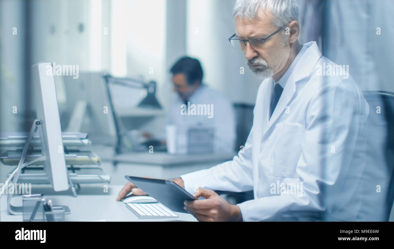 Senior Medical Practitioner Sitting Before Personal Computer Uses ...