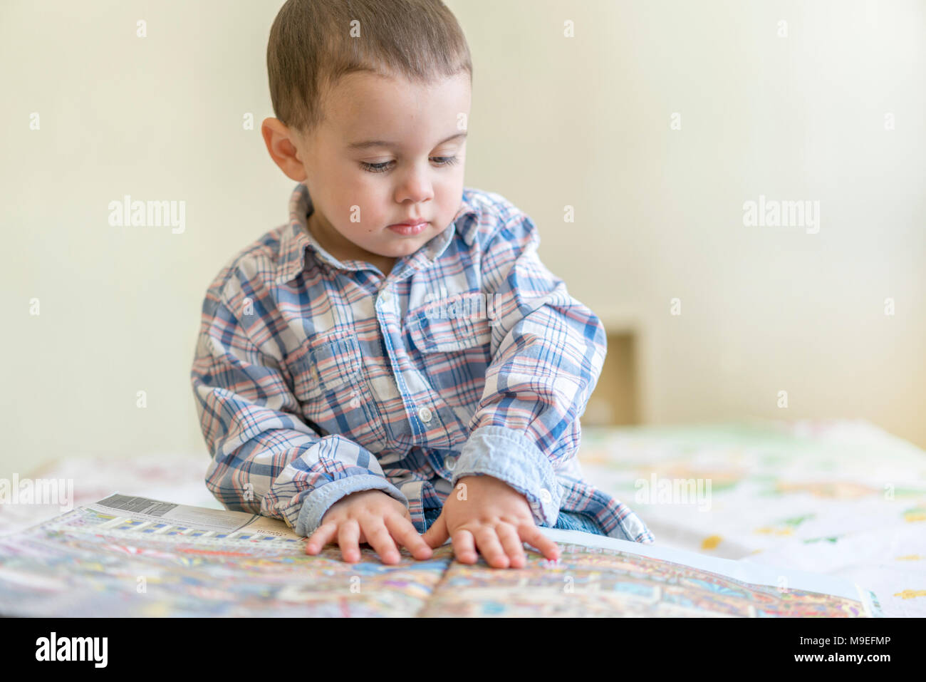 A beautiful little boy is looking at a big book Stock Photo - Alamy
