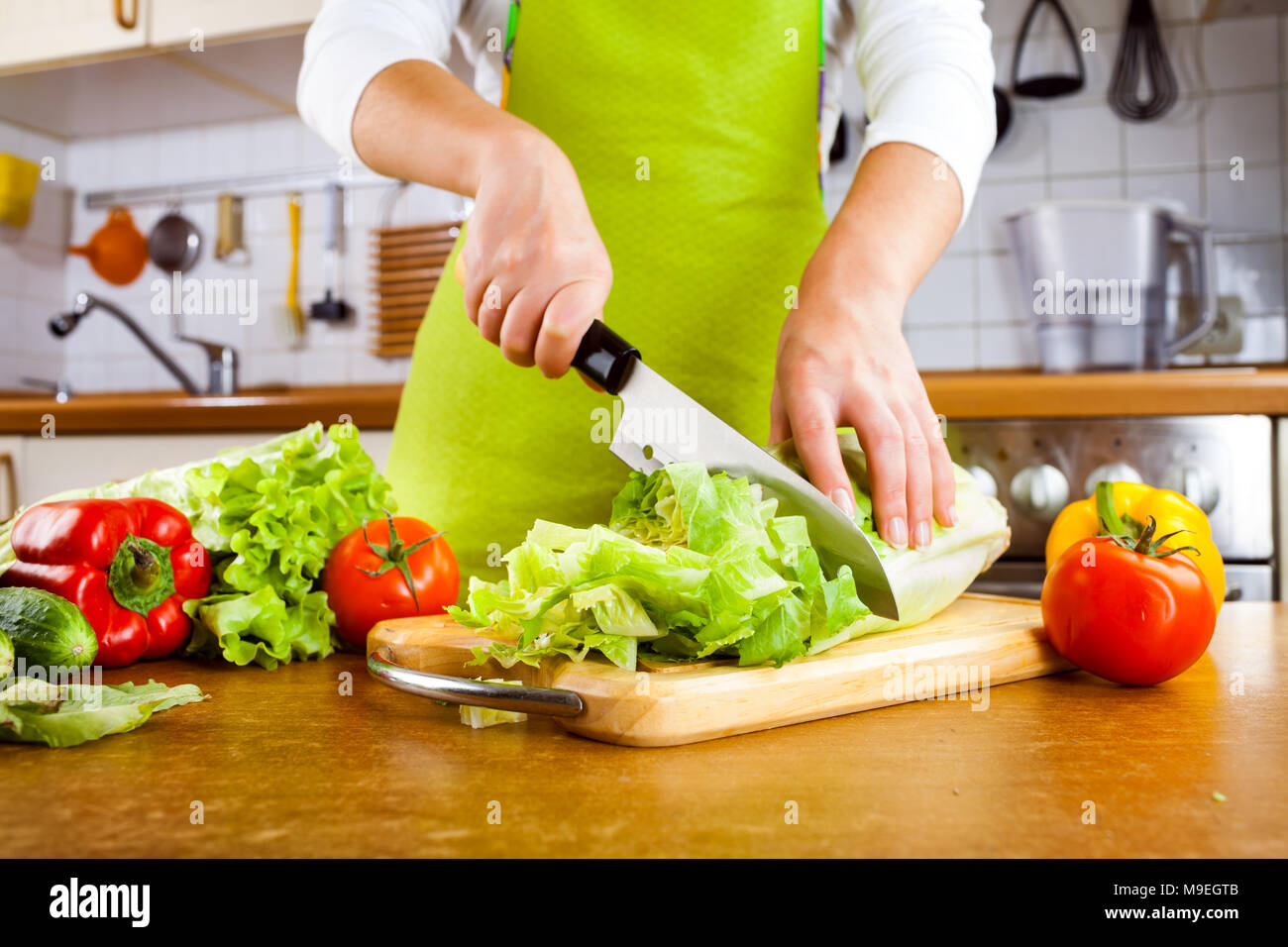 Woman's hands cutting lettuce, behind fresh vegetables Stock Photo - Alamy