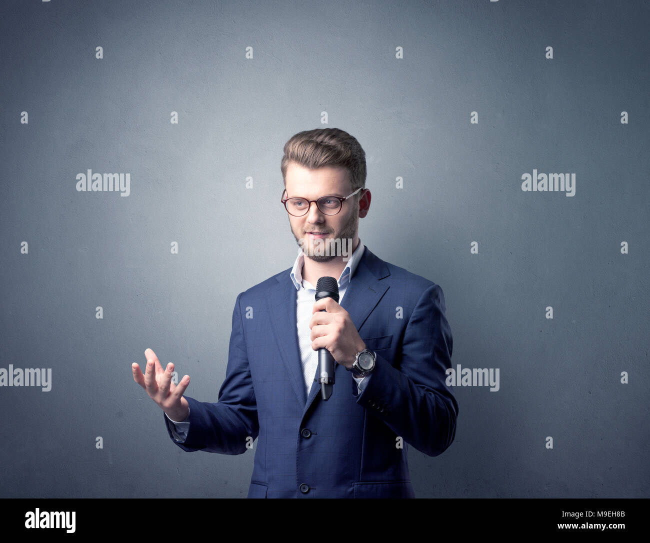 Businessman speaking into microphone with blue background Stock Photo ...